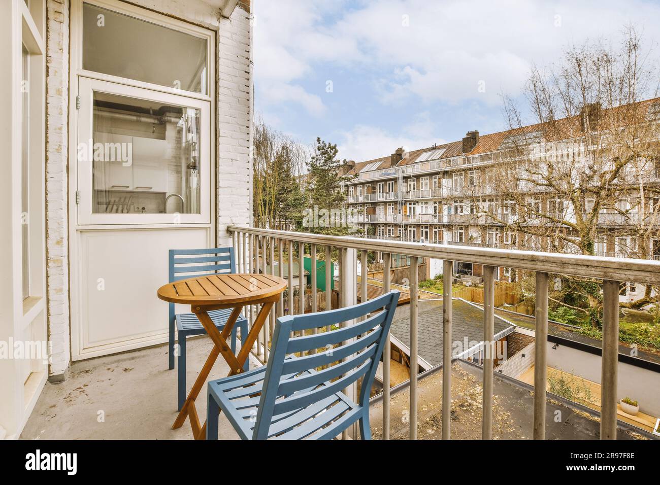a balcony with two blue chairs and a table on the left side, looking ...