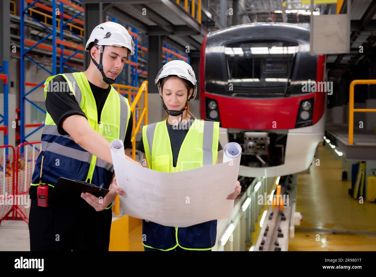 Young caucasian engineer man and woman or worker looking blueprint and ...