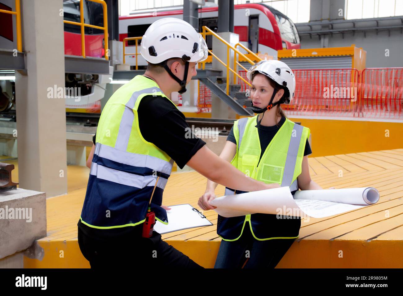 Young caucasian engineer man and woman or worker looking blueprint and ...