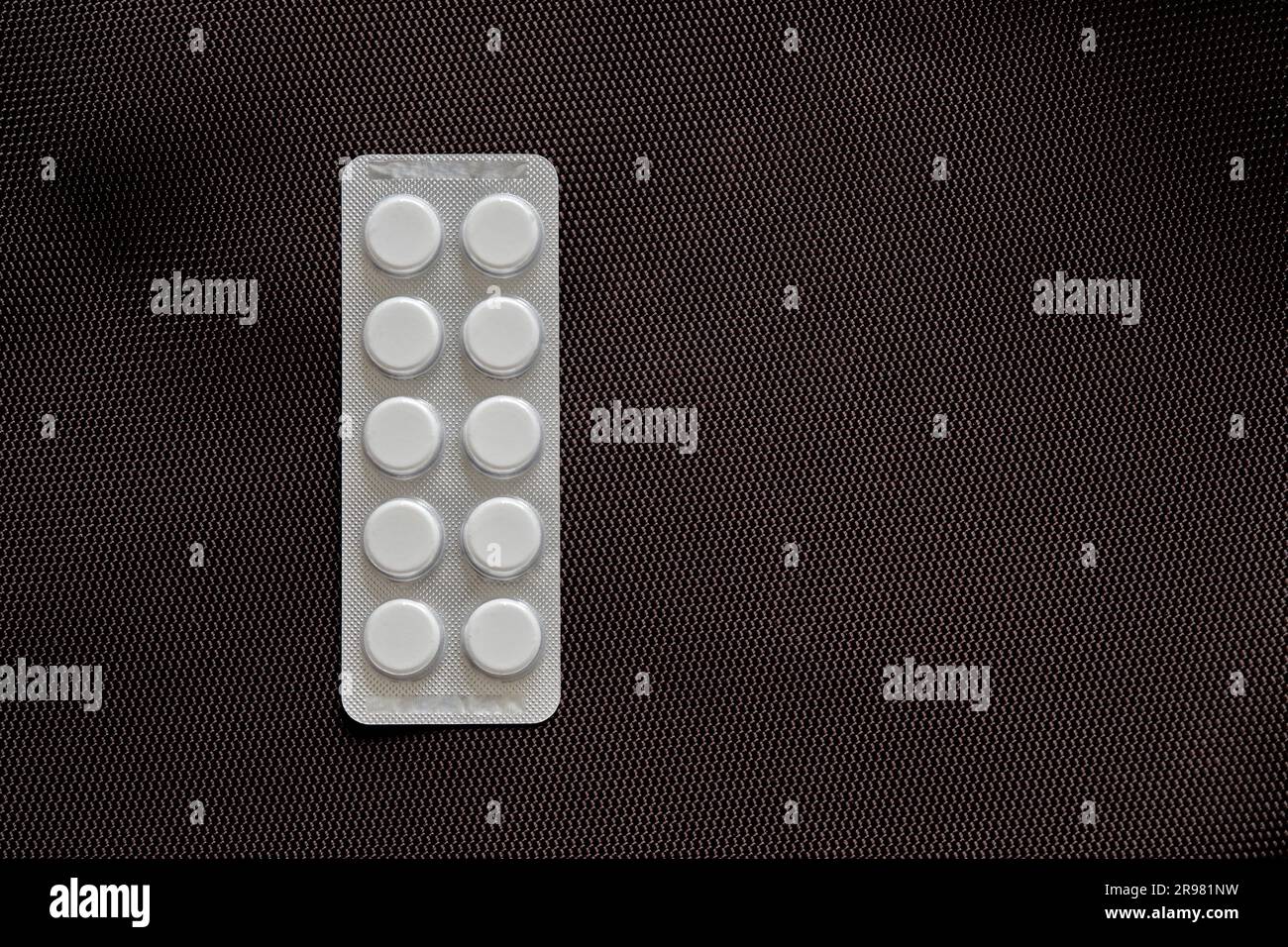 Package of round pharmaceutical medicine drug tablets on a dark rough ...