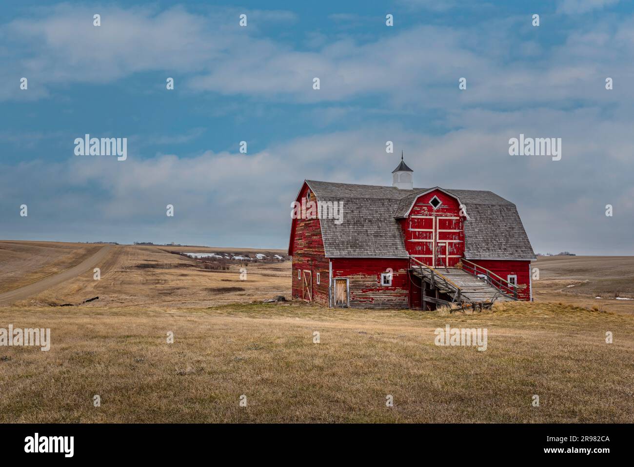 An abandoned red barn with a wagon ramp on the prairies in Saskatchewan ...