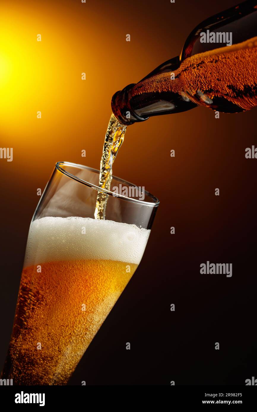 Pouring beer from a bottle into a tall glass Stock Photo - Alamy
