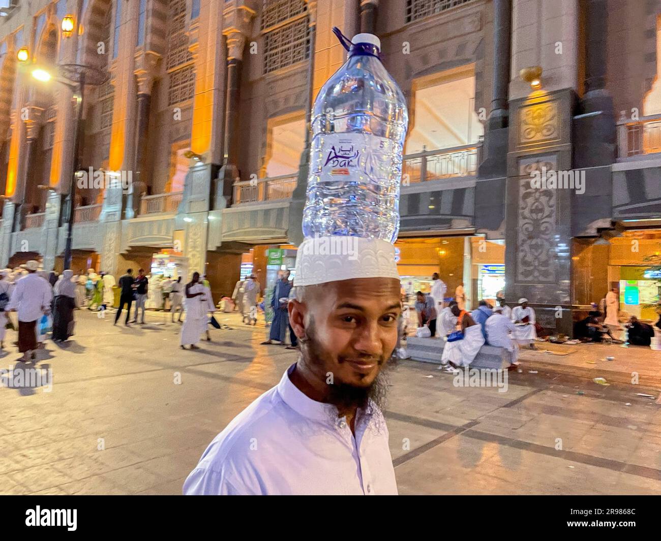 A Bengali pilgrim carries a water bottle over his head outside the ...