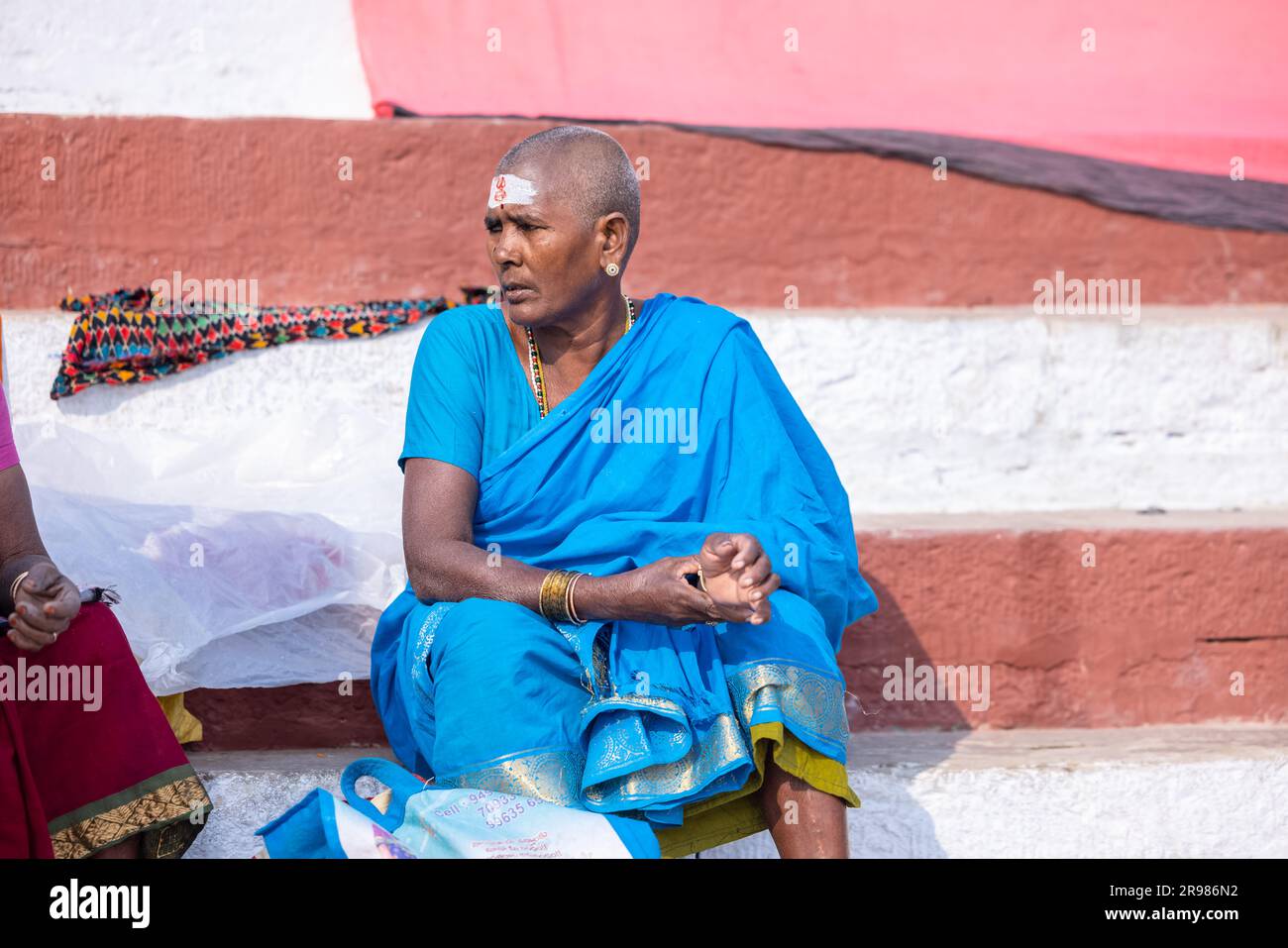 Portrait on an old south indian woman with shaved head sitting on ...