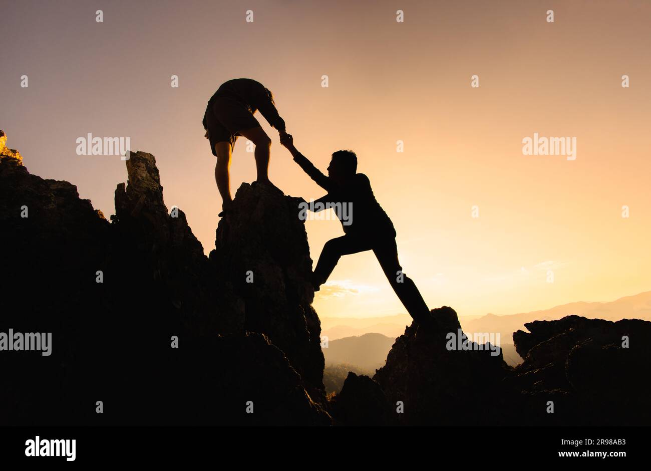 Concept of business, Hikers climbing up mountain cliff and one of them ...