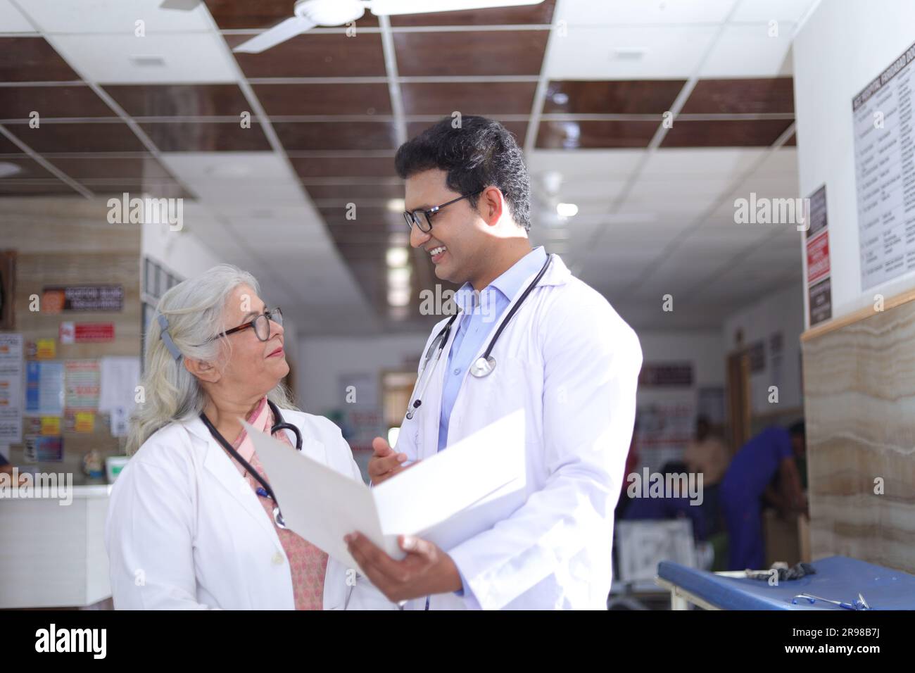 Older woman doctor and young male doctor. Doctor reading patient report ...