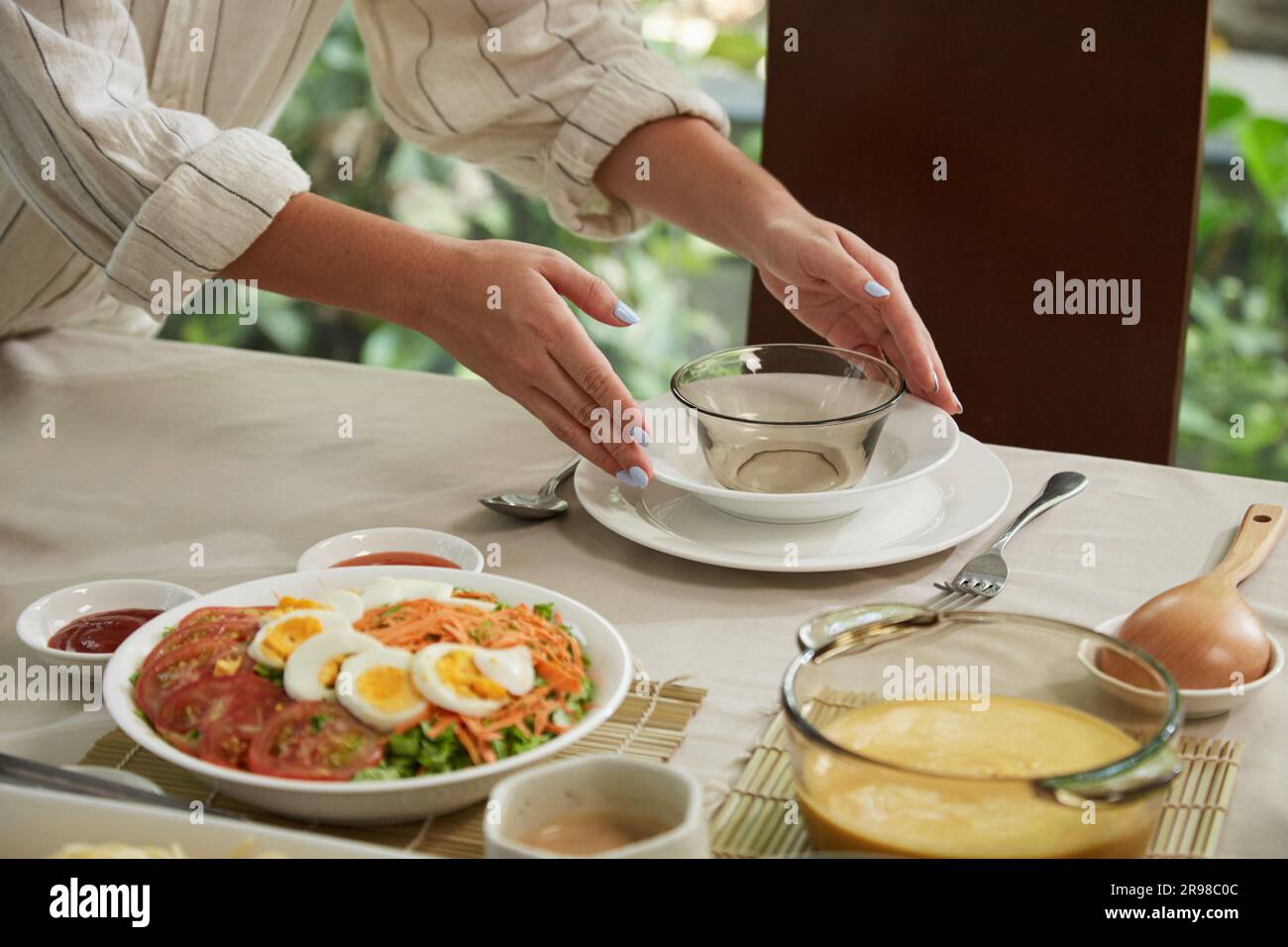 Woman putting plates on table hi-res stock photography and images - Alamy
