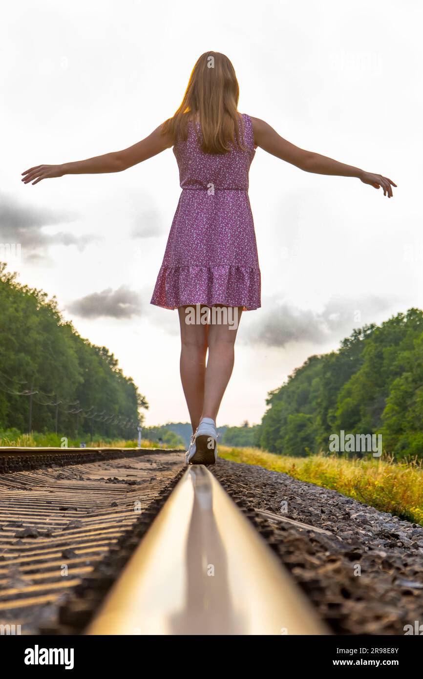 A girl in a dress walks along the rails Stock Photo - Alamy