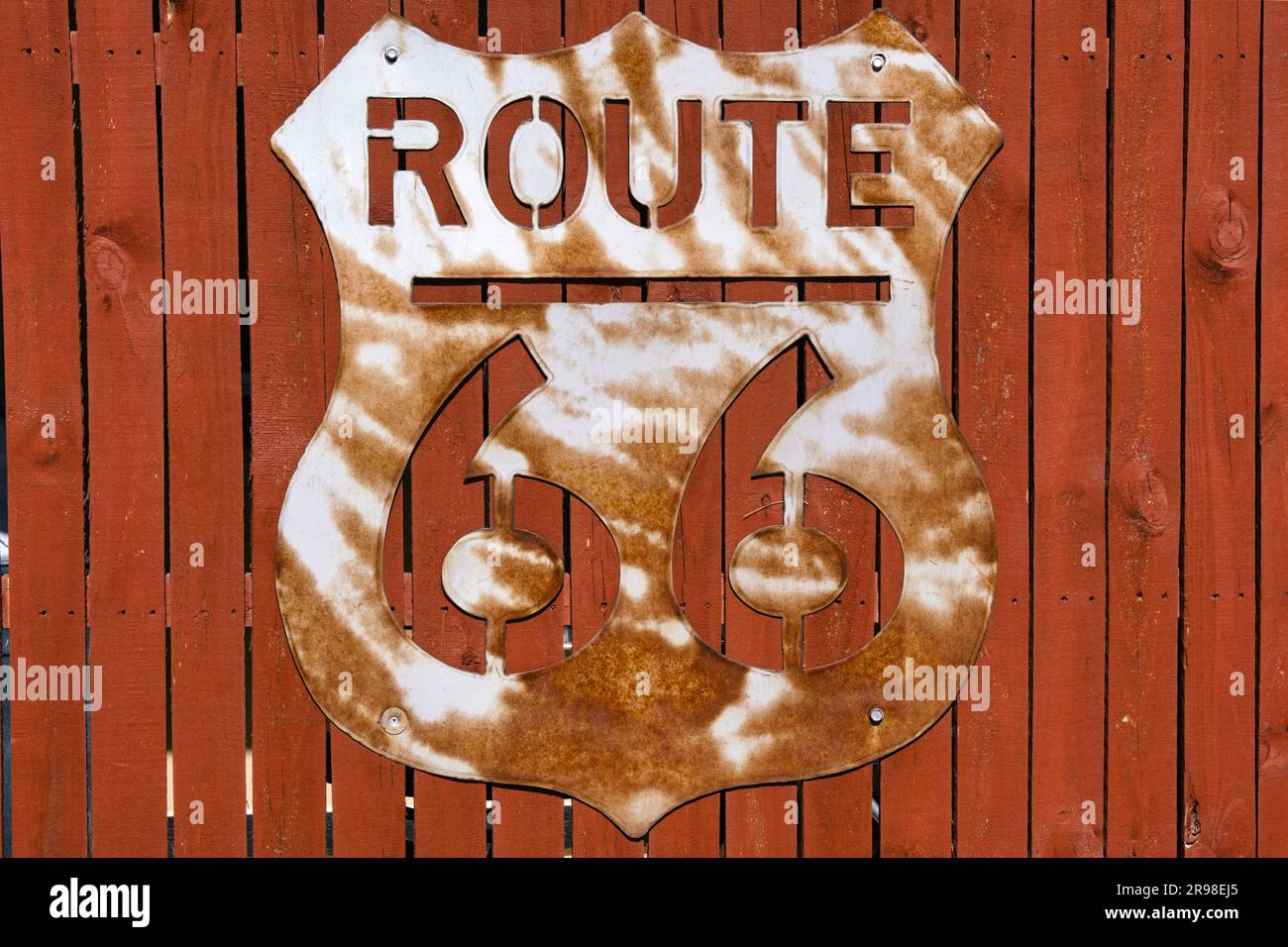 An aged, rust-painted wooden fence featuring a vintage Route 66 road ...
