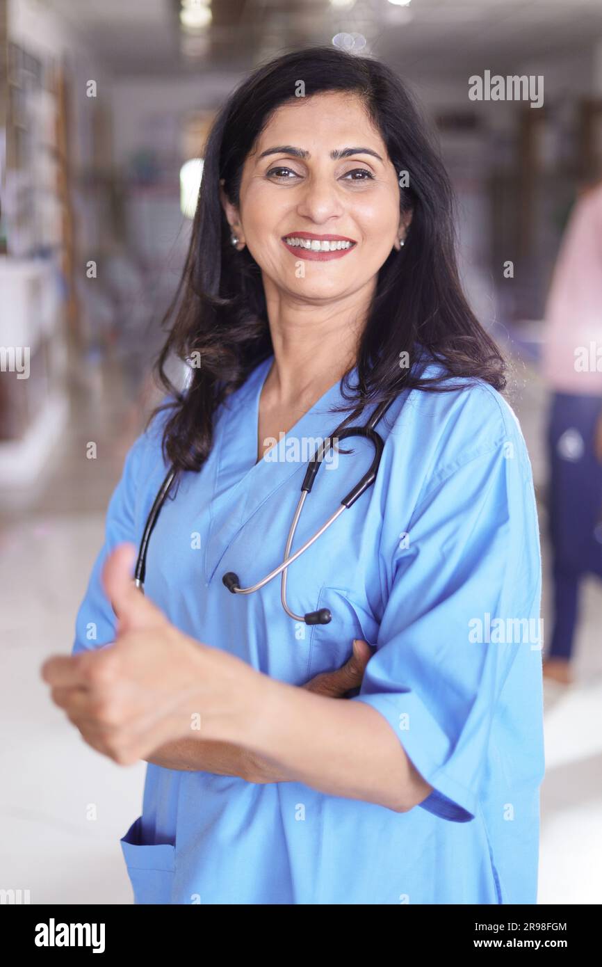 Portrait of female doctor showing thumbs up. Happy nurse in blue ...