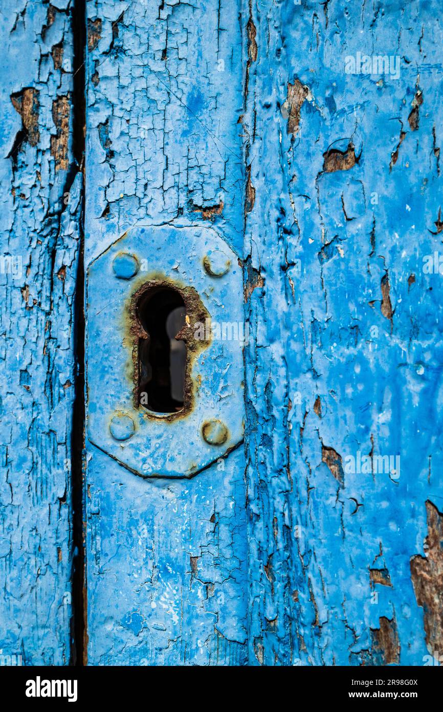 Closeup view of the keyhole in an ancient blue wooden door with rough ...