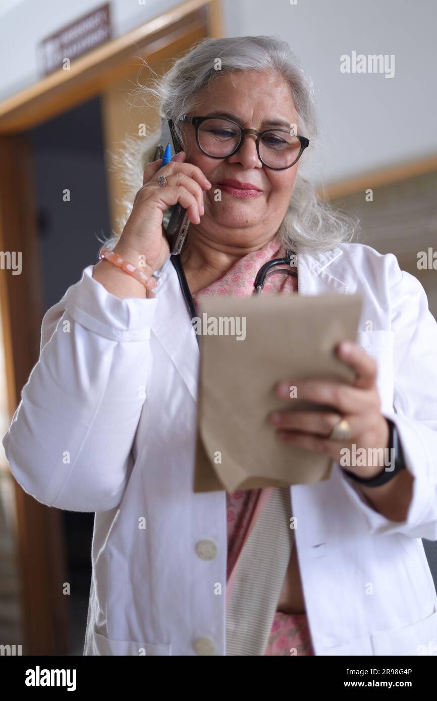 Portrait of smart senior female doctor in white lab coat talking over a ...