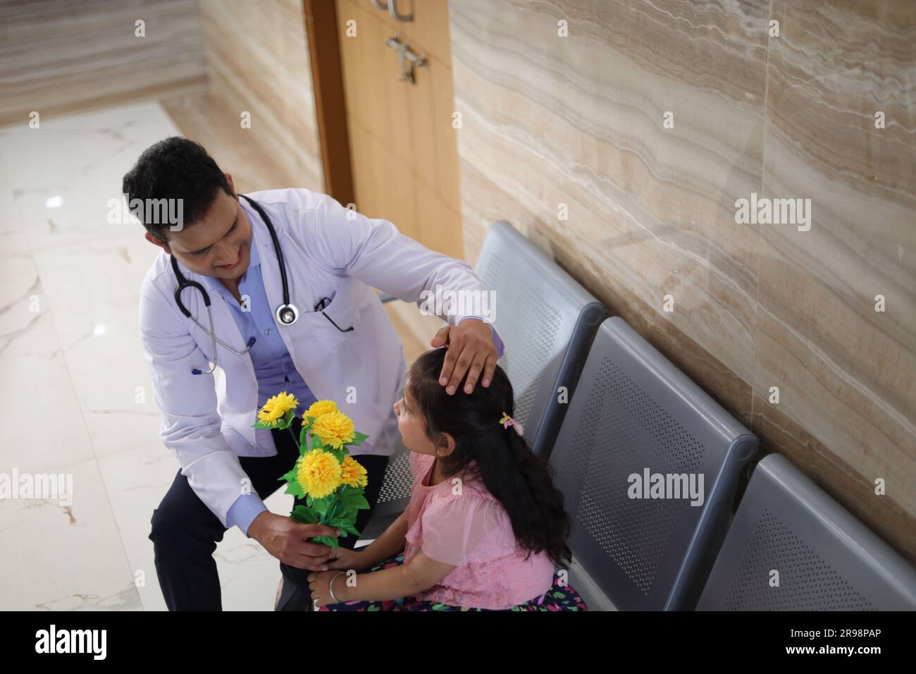 Happy girl child sitting on bench in hospital corridor, senior doctor ...