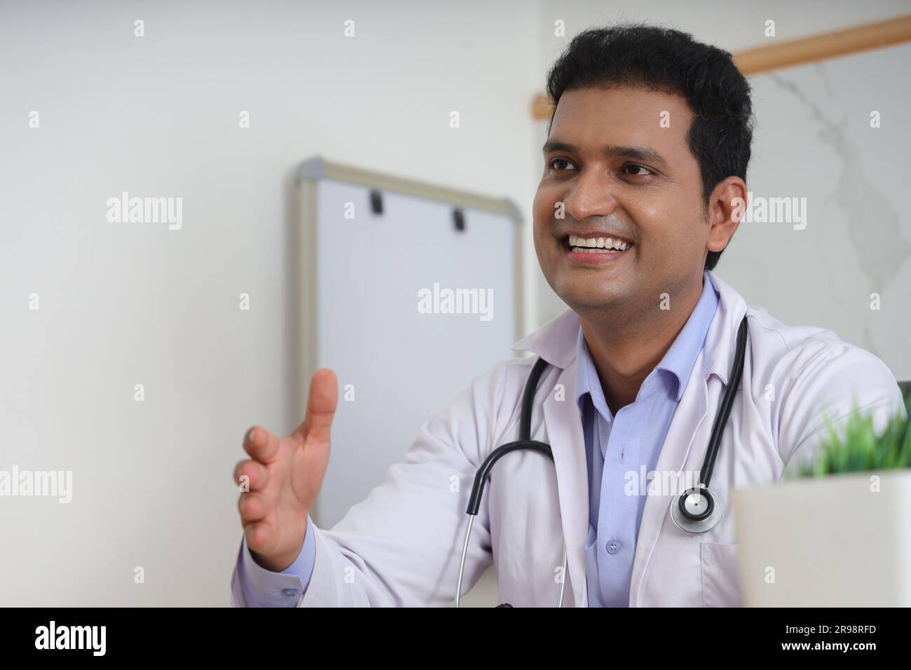 young Indian doctor sitting with patient having a detailed conversation ...