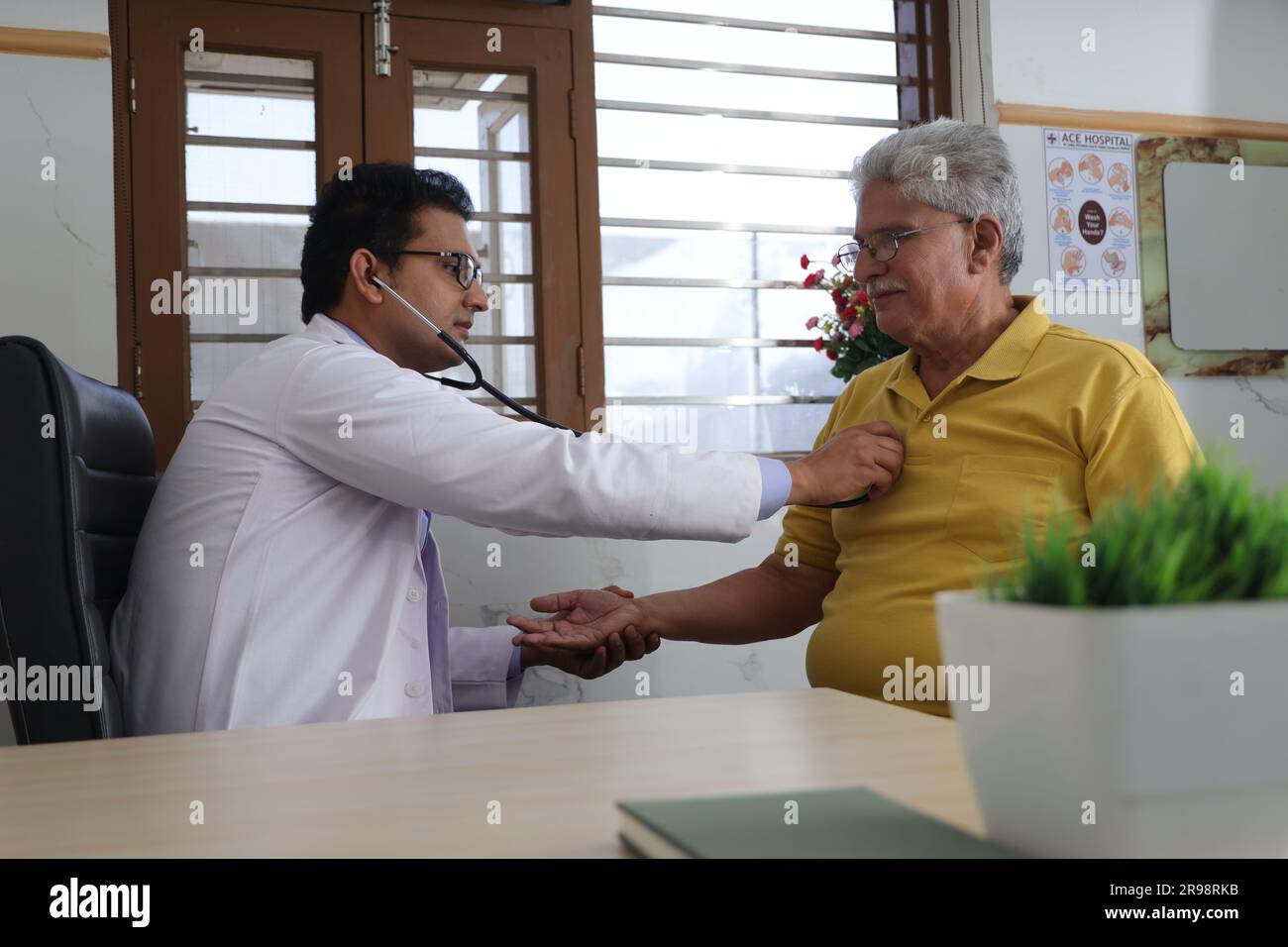 young doctor sitting with senior patient in the doctor's office ...