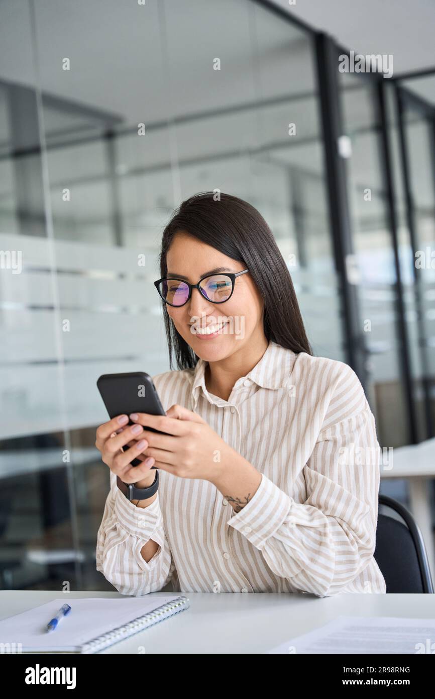 Happy Asian female employee using cell phone working in office Stock ...