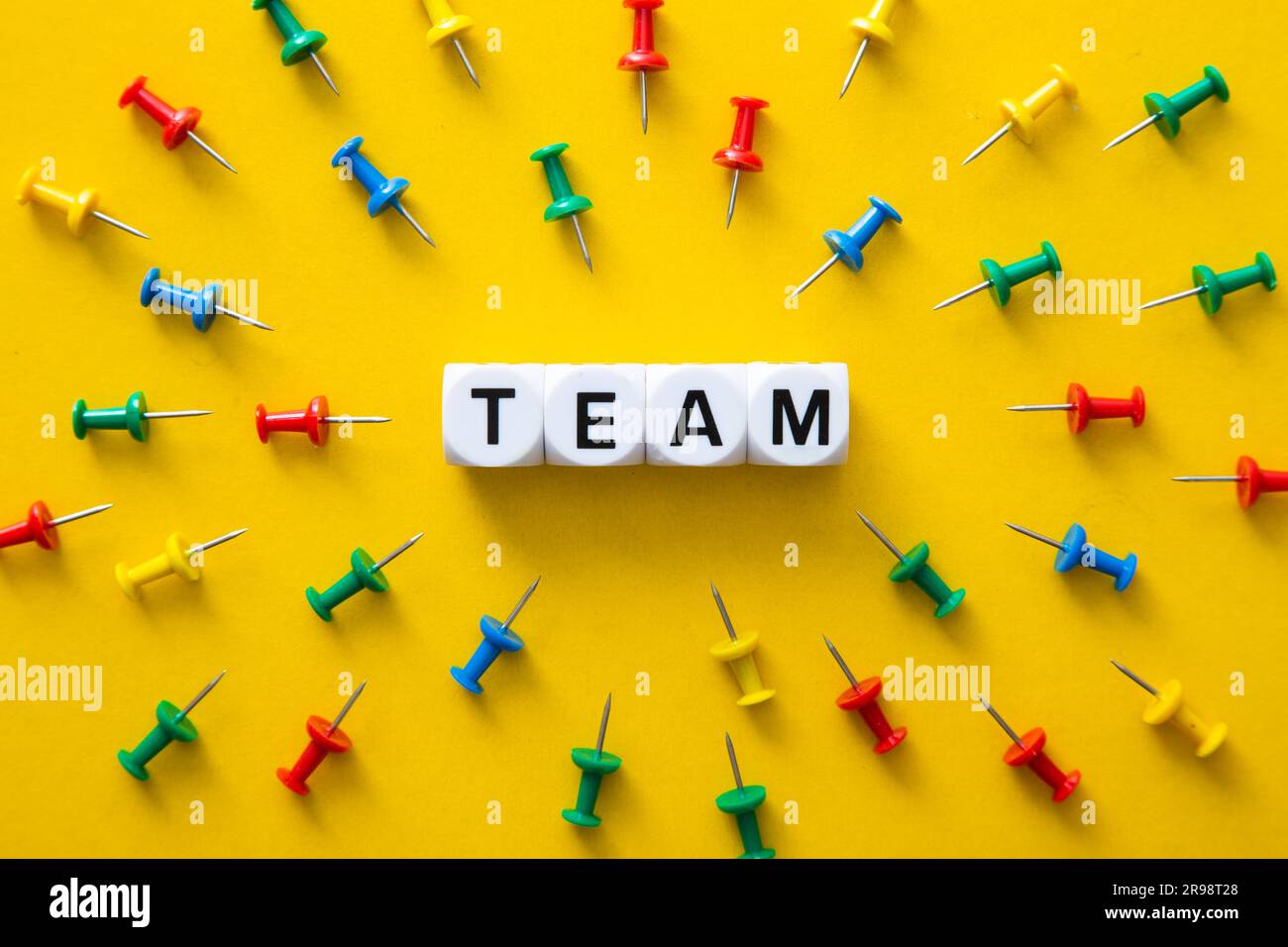 A vibrant yellow background with a team word and various colorful pins ...