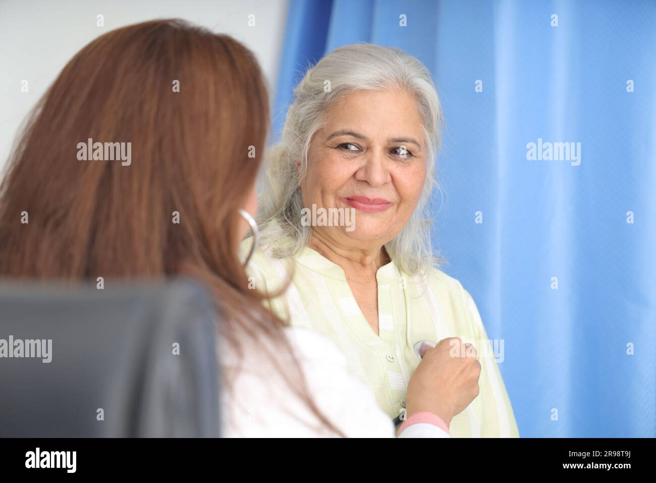 young doctor sitting with senior patient in the doctor's office ...