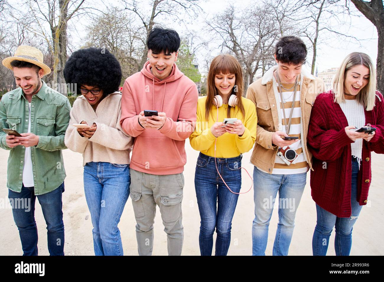 Group of multiracial young cheerful students watching their mobiles ...