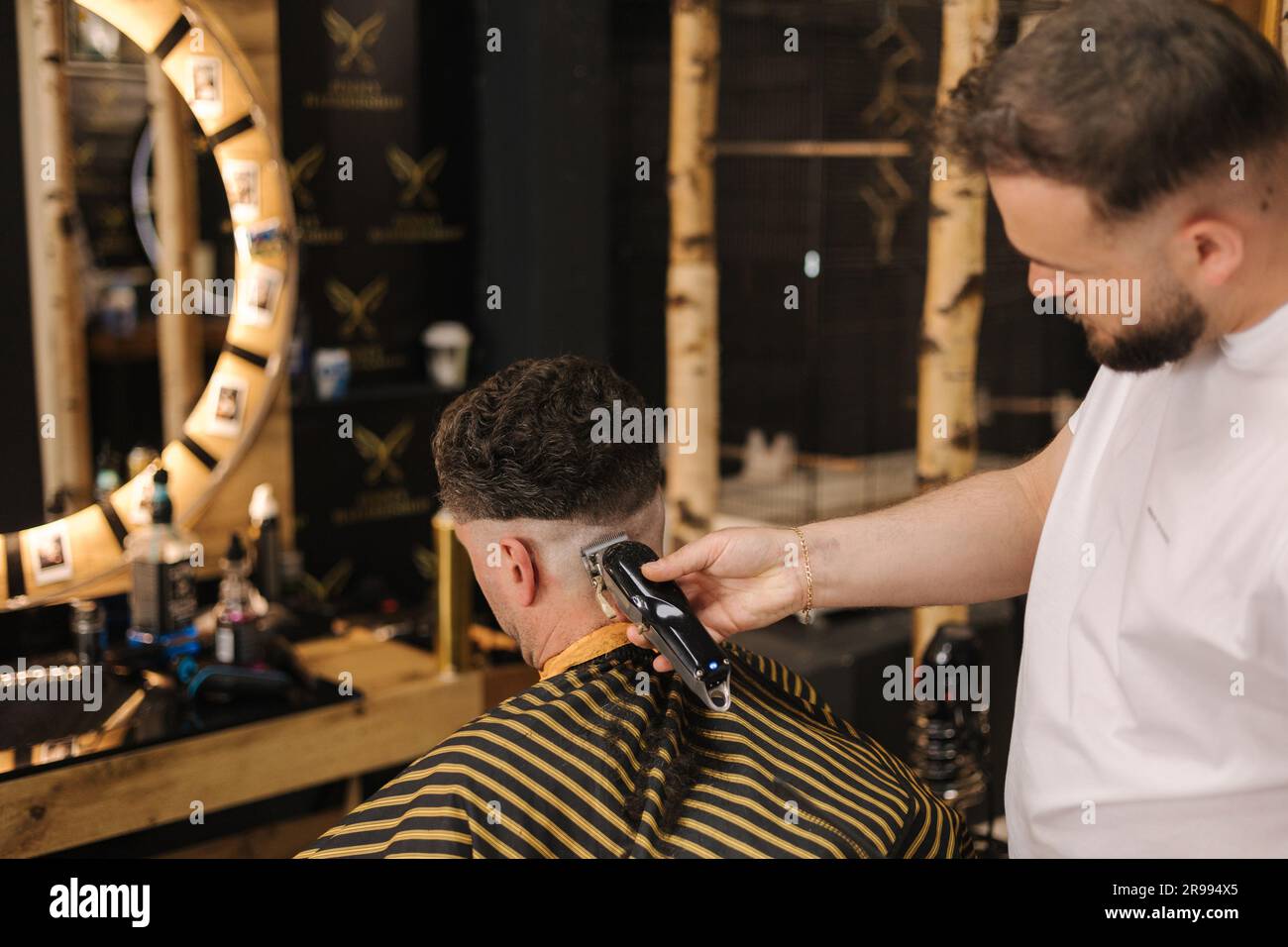 Man sitting in barber shop during barber have cut his hair. Back view ...
