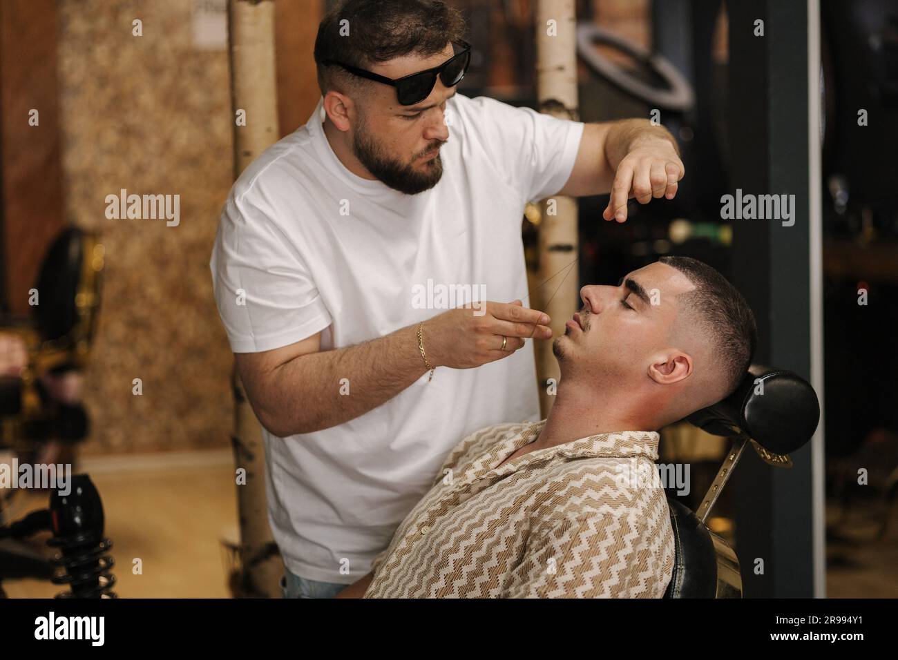 Side view process of threading procedure in barber shop. Professional ...