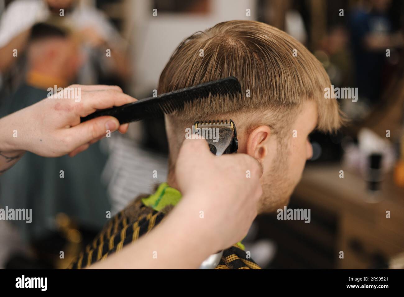 Back view of barber using trimmer to make haircut for customer Stock ...