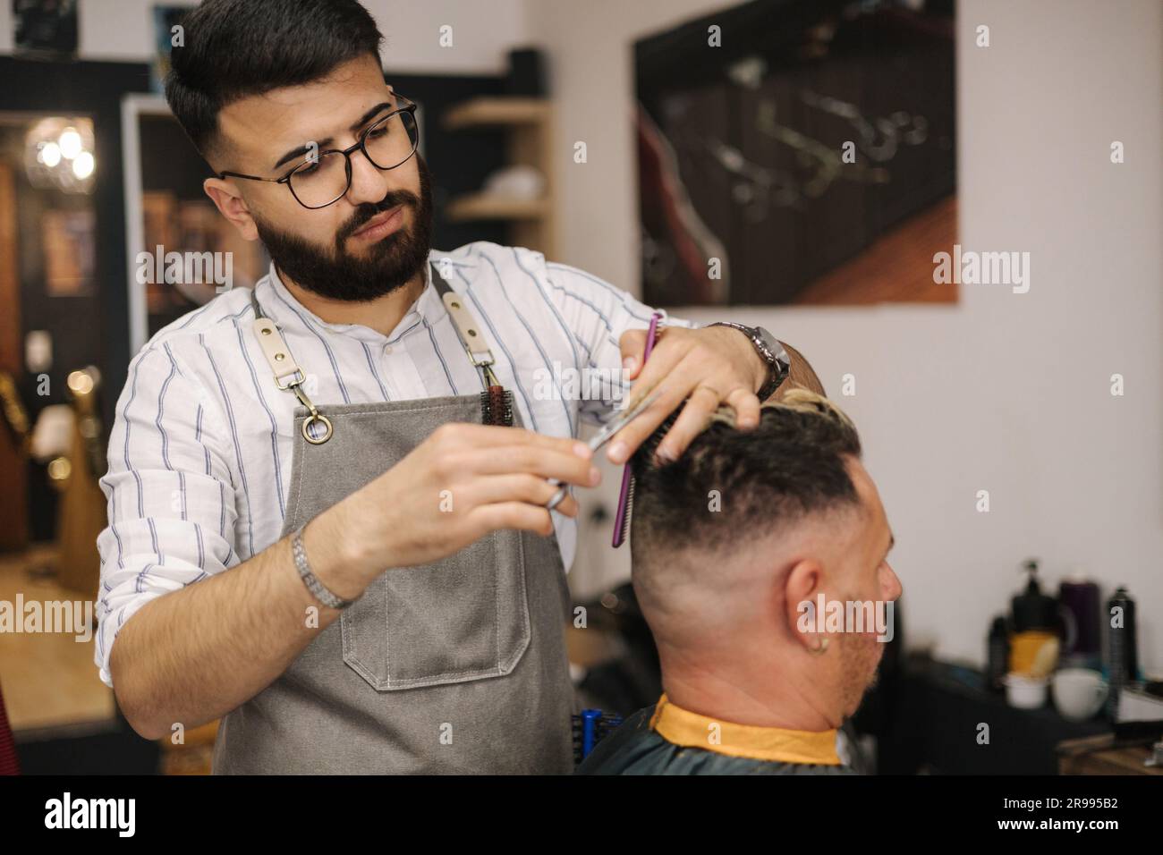 Side view of barber using scissors and making hairstyle. Modern ...