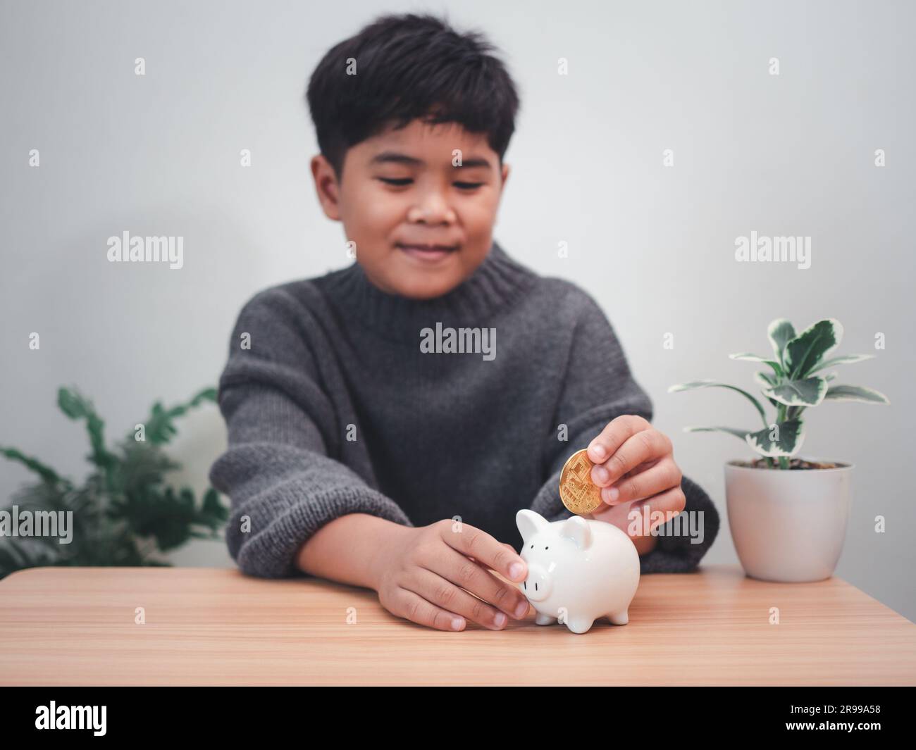 A boy putting coins into piggy bank. Learning financial responsibility ...