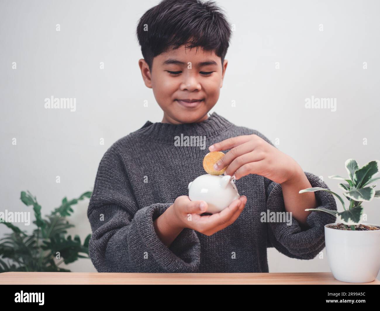 A boy putting coins into piggy bank. Learning financial responsibility ...