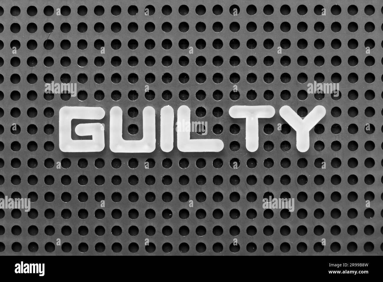 White alphabet letter in word guilty on black pegboard background Stock ...