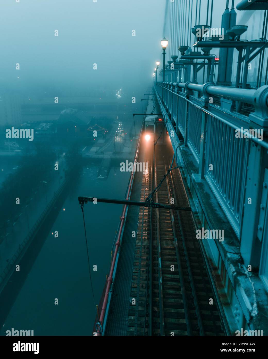 A modern passenger train traveling along a bridge illuminated by the ...