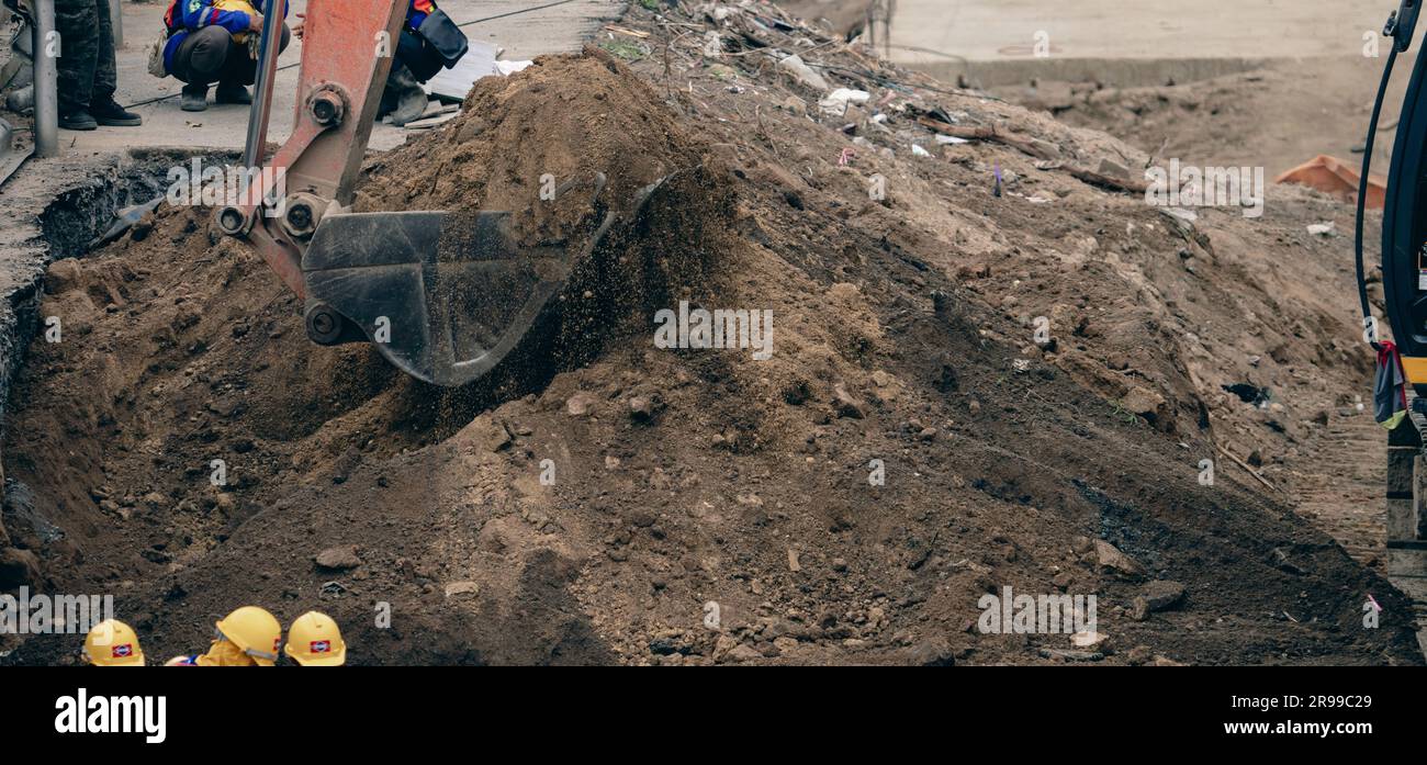 Backhoe working by digging soil at construction site. Bucket teeth of ...
