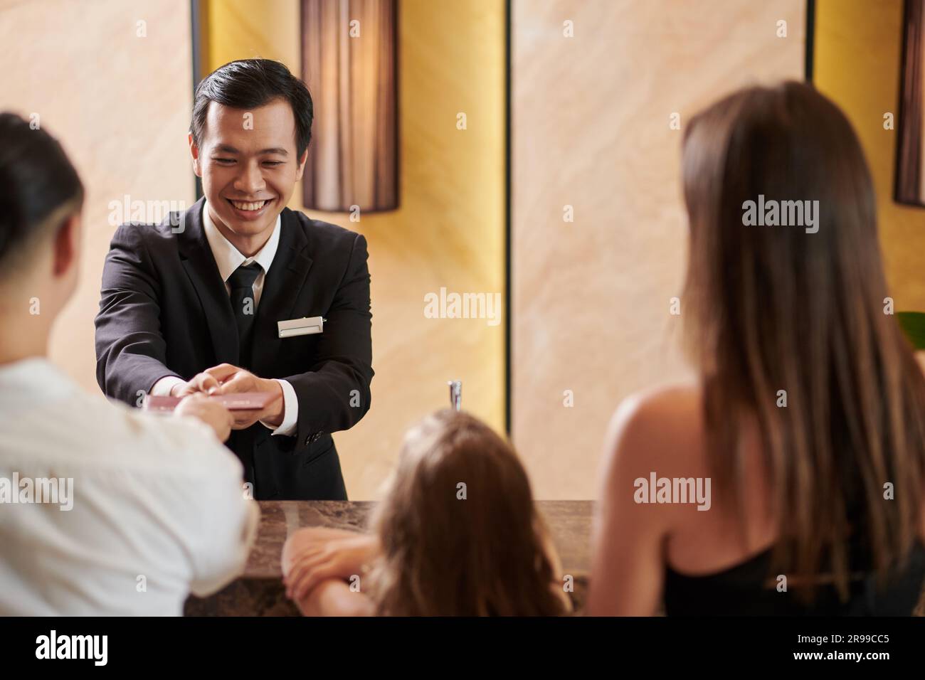 Smiling hotel receptionist asking guests to give him passports Stock ...