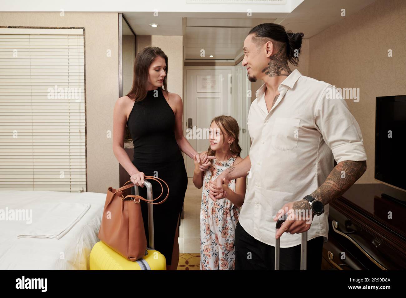 Family of three with suitcases standing in hotel room they booked for ...