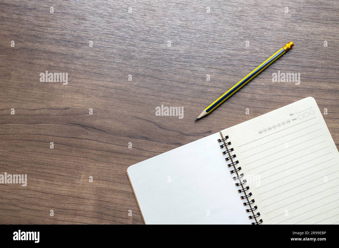 A view of a wooden desk from above with an open notebook and pen. blank ...