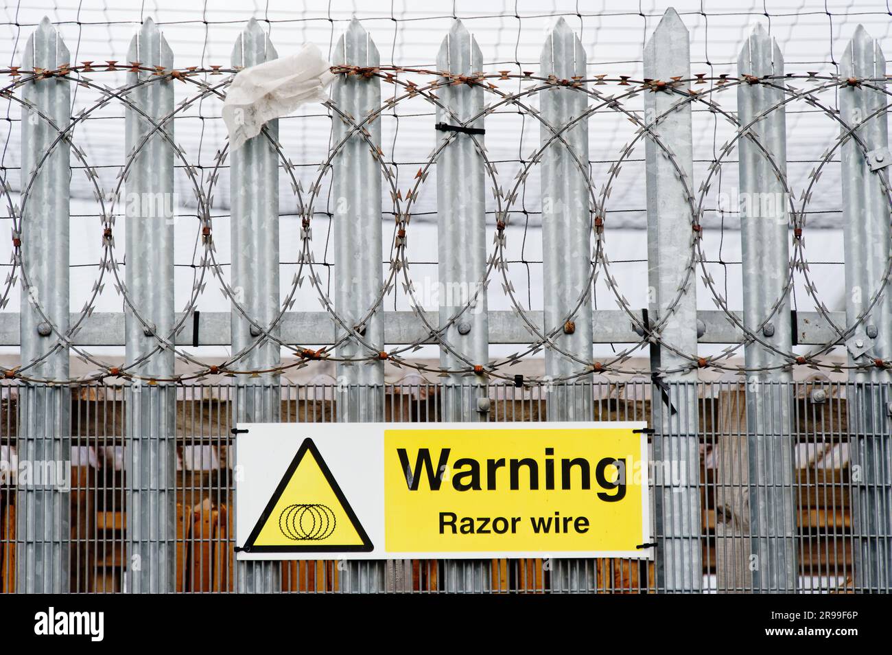 Razor wire warning sign on security fence at construction site Stock ...