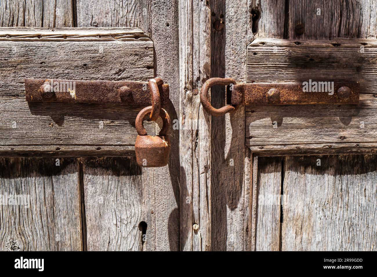 Closeup view of an antique padlock in an ancient wooden door with rough ...