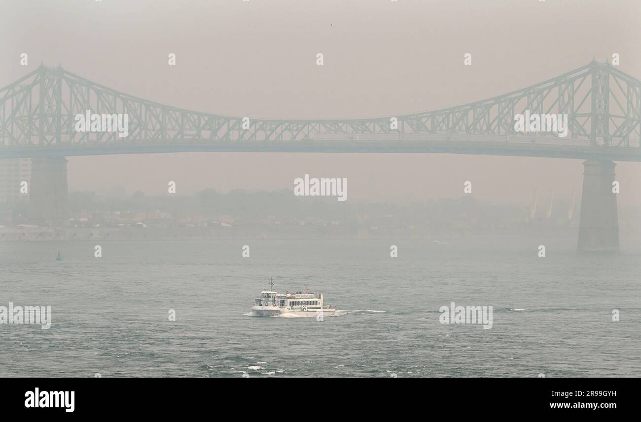 A boat passes by the Jacques Cartier bridge obscured by a haze of smog ...