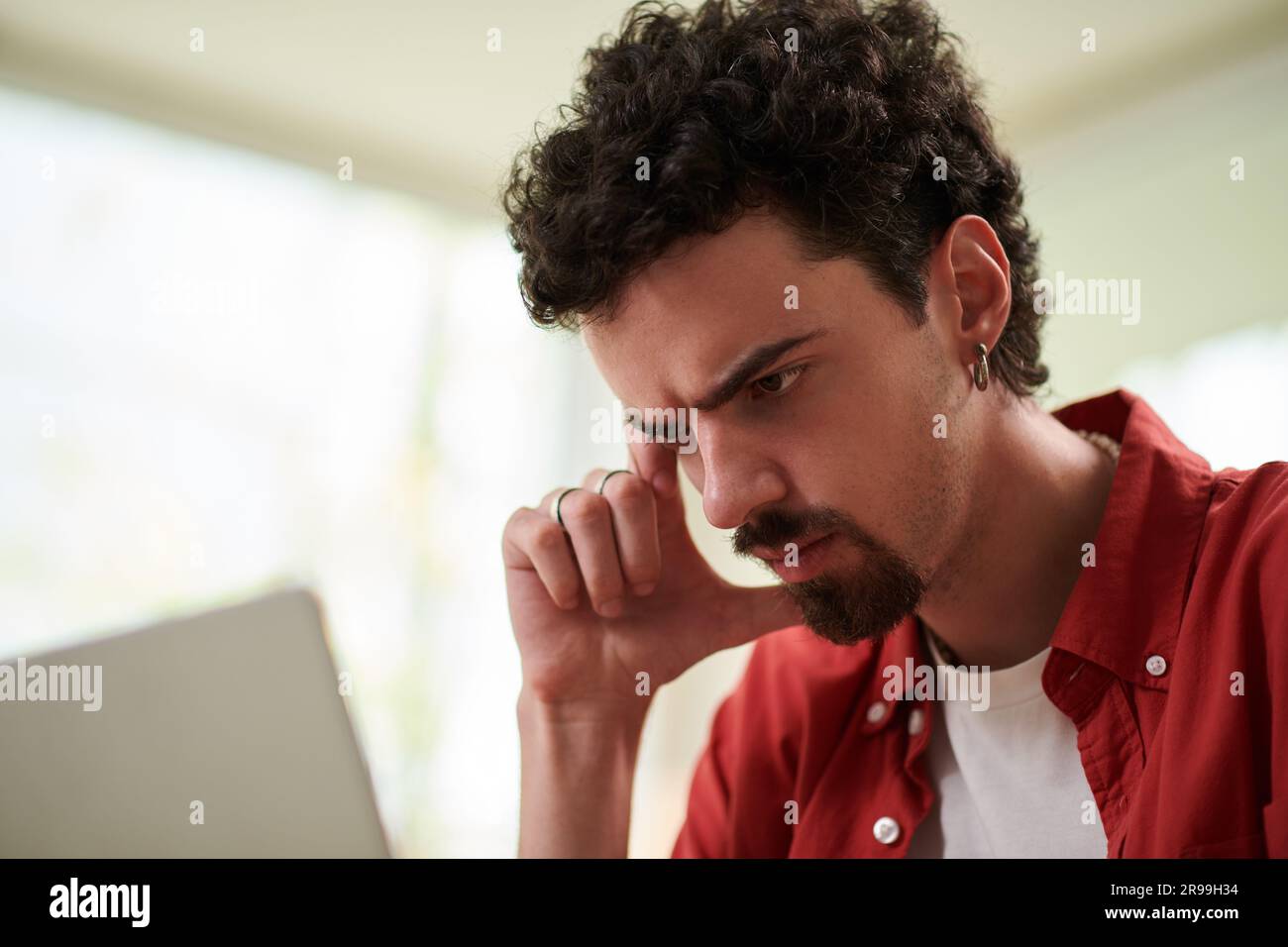 Pensive man checking programming code for errors when working on laptop ...