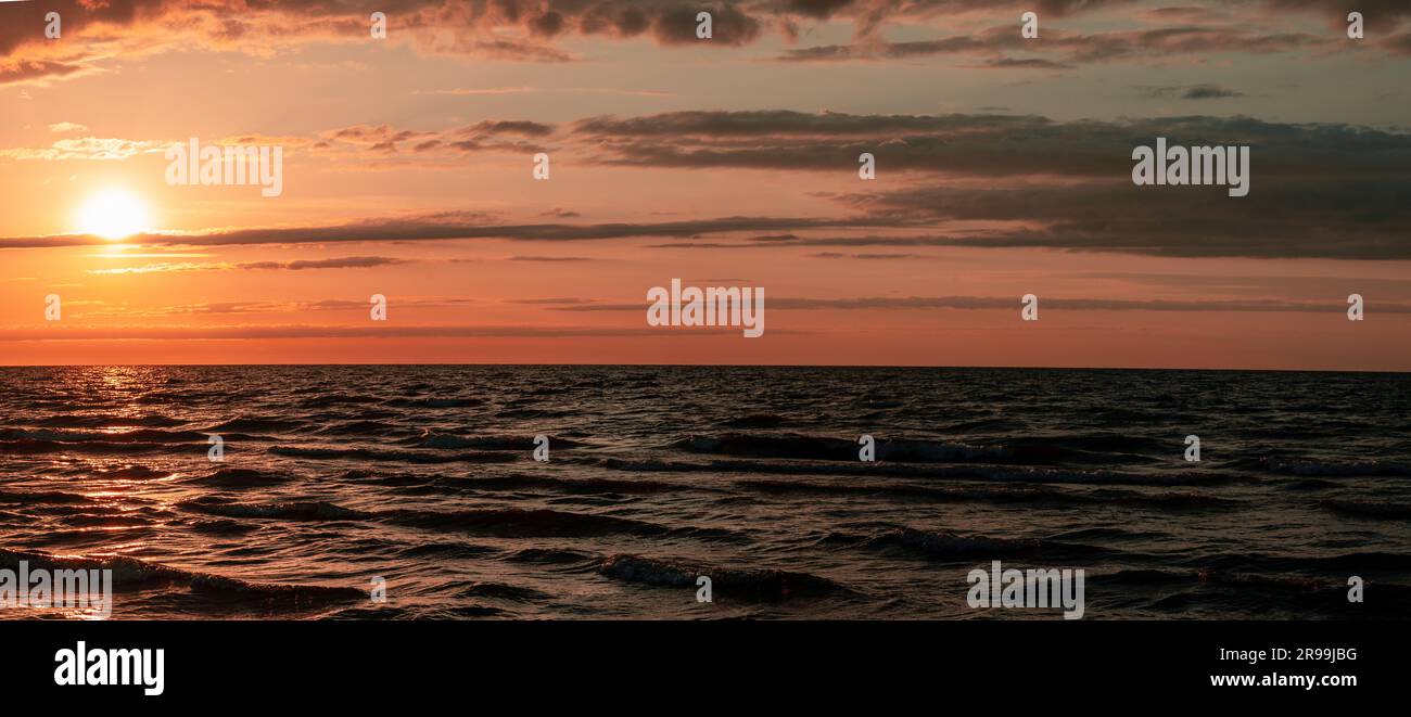 Panorama with an unforgettable gentle sunset on the sea with waves. The ...
