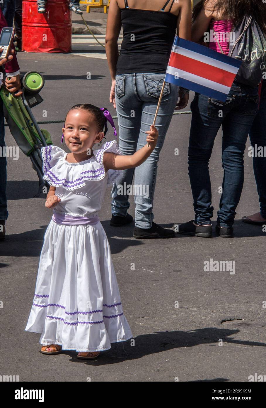 Young girl in traditional dress proudly holds a Costa Rican flag at an ...