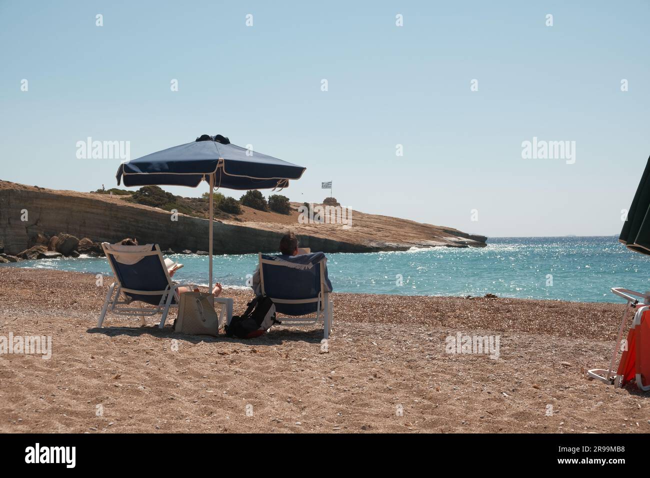 View of two tourist on the Fourni Beach. They are sitting on the sunbed ...