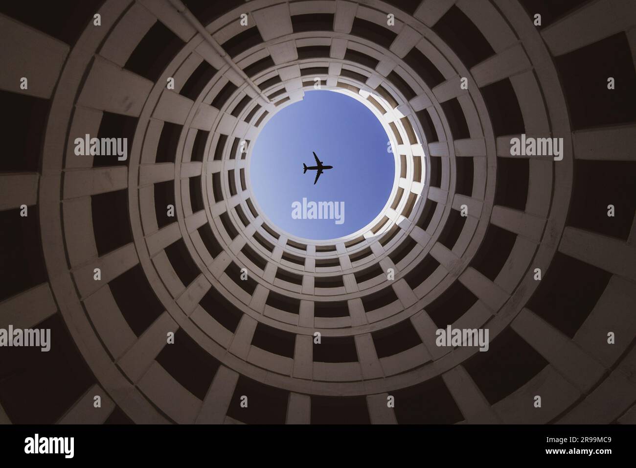 A low angle of an airplane soaring high above a contemporary spiral ...