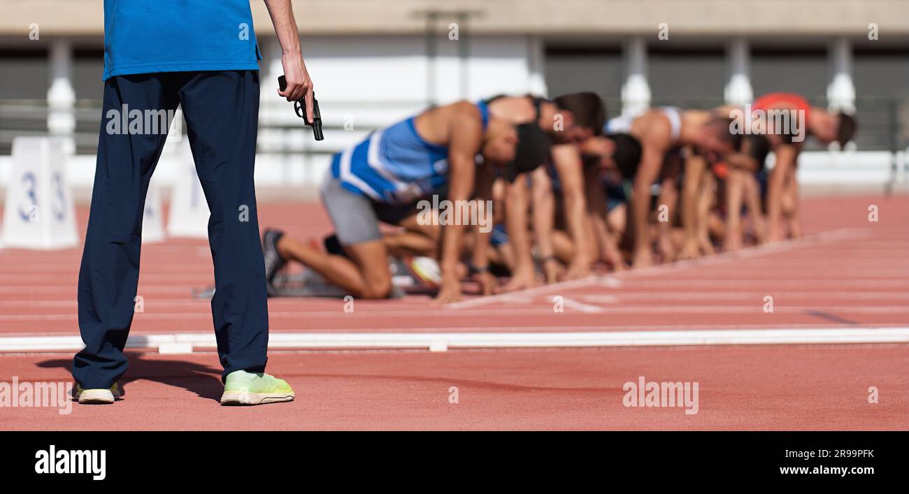 Athletes ready to start in blocks, starter with gun, official prepares ...