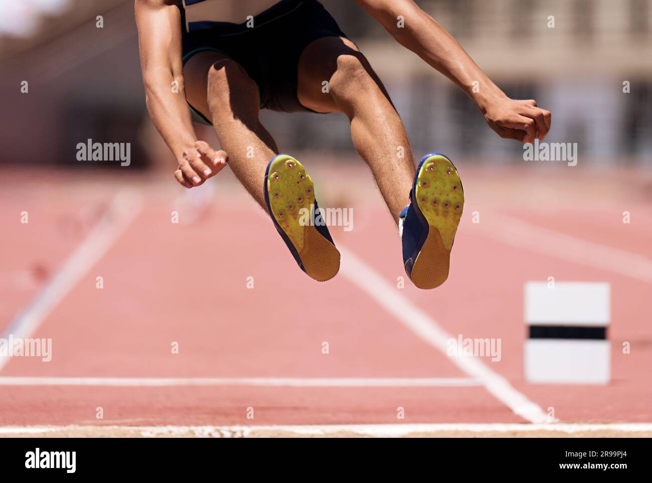 Male athlete performing a long jump during a competition at stadium ...
