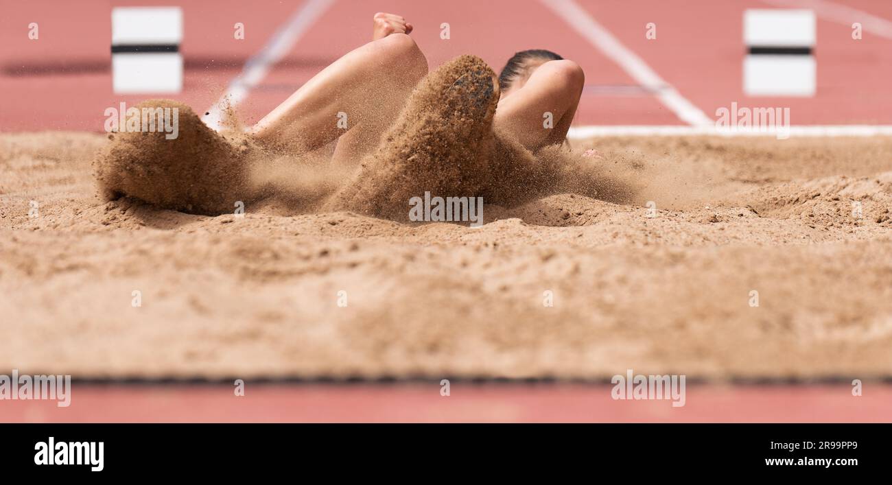 Female athlete long jump landing sand spray, landing in long jump in ...