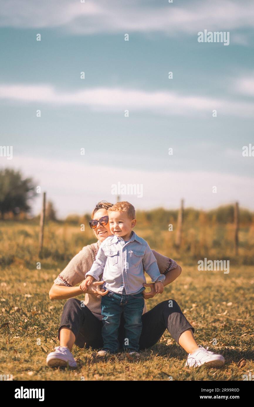 A loving mother and her son embrace in a sun-kissed field, radiating ...
