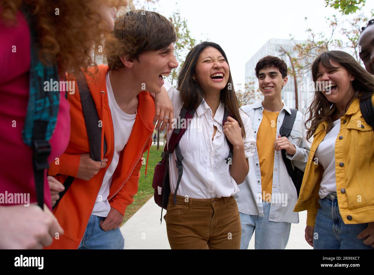 Diverse group of smiling young students gathered outside college campus ...