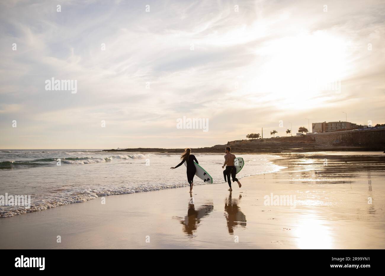 Wave Runners. Young Couple With Surfboards Going Into The Ocean Stock ...