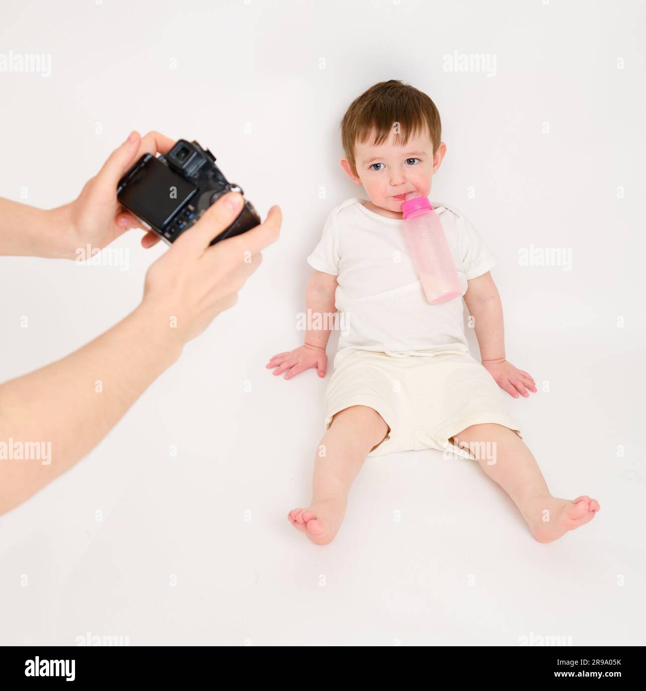 Woman mother photographs baby on photo camera, studio white background ...